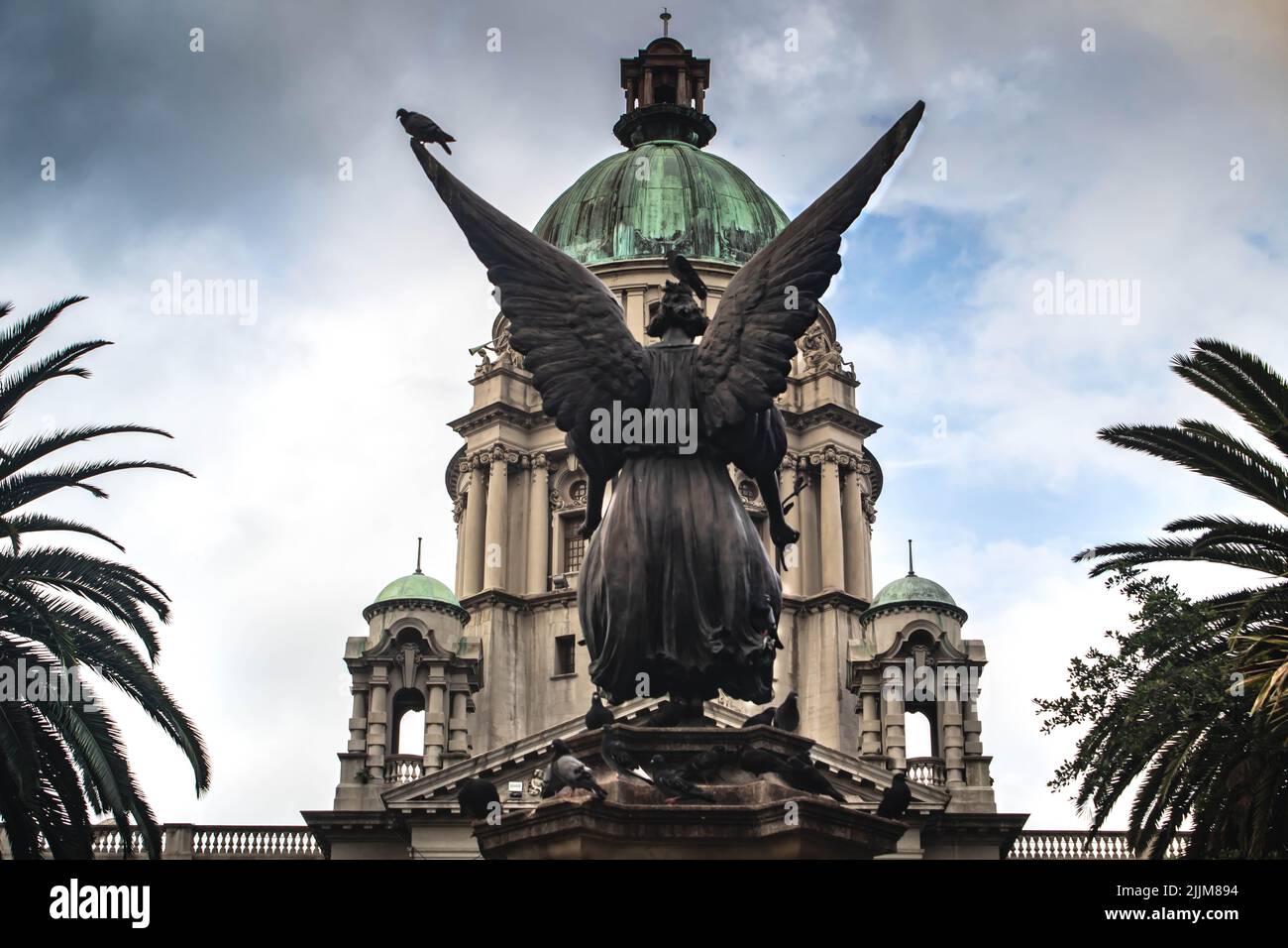 An angel sculpture from behind in front of the building Stock Photo - Alamy