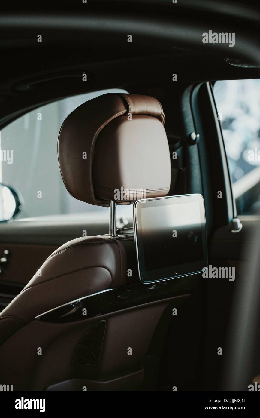 A vertical shot of headrest and a tablet in a luxury black car showroom ...