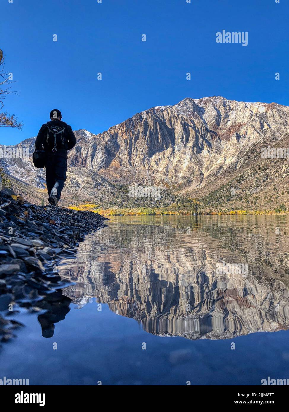 A vertical back view of a hiker at Convict Lake, California, in the ...