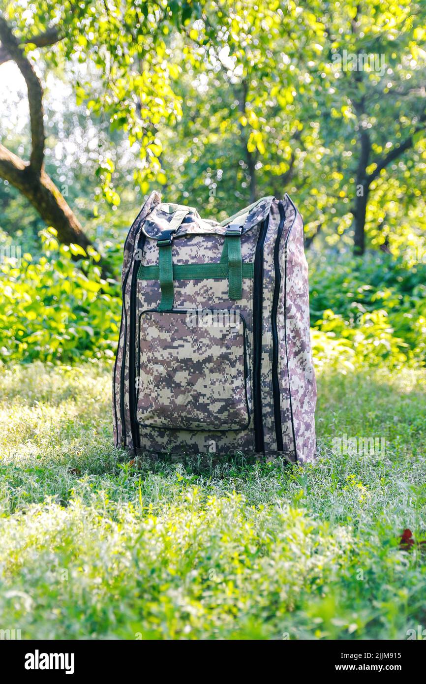 Defocus military backpack. Army bag on green grass background near tree ...