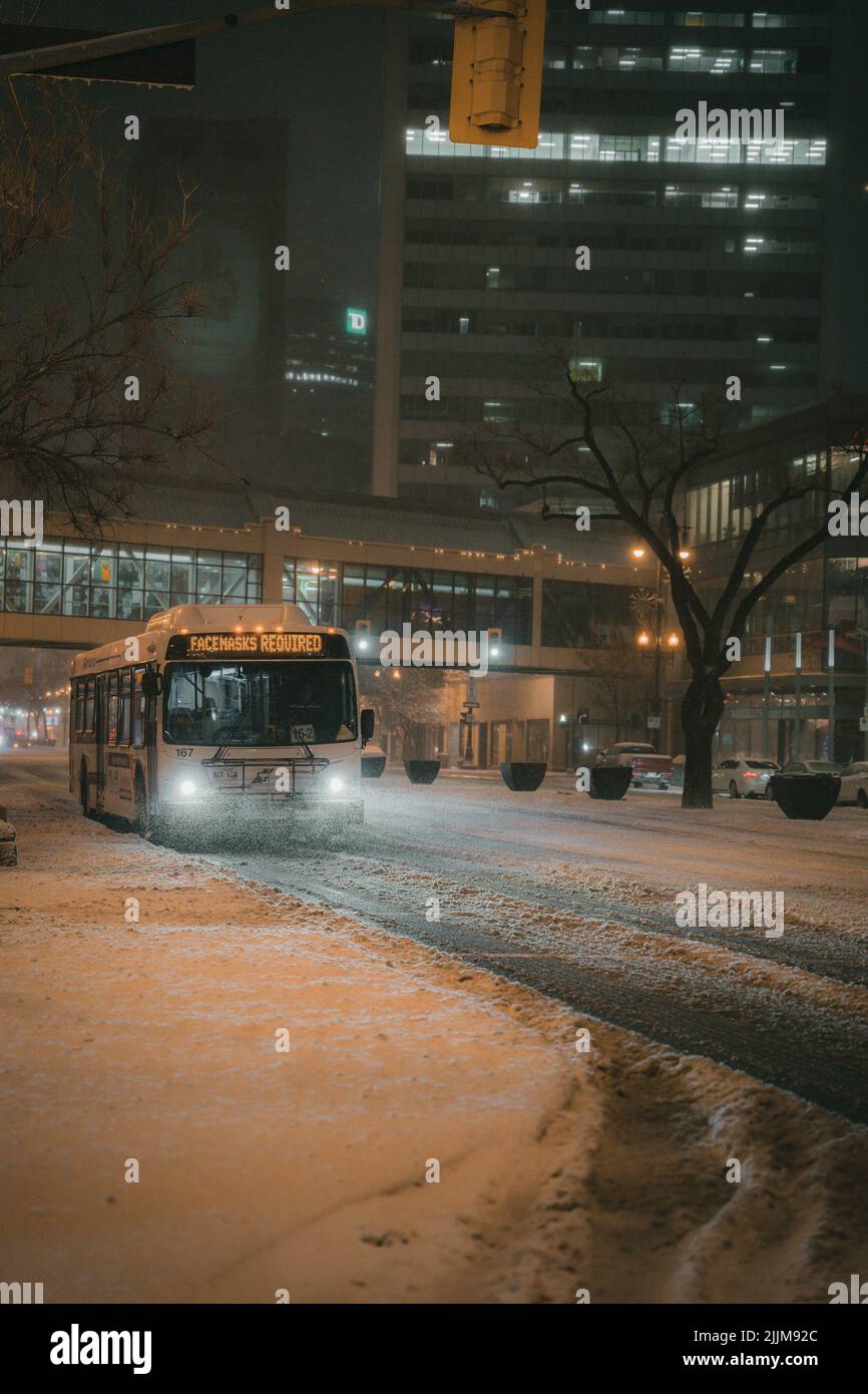 A bus on a snowy city street at night Stock Photo - Alamy