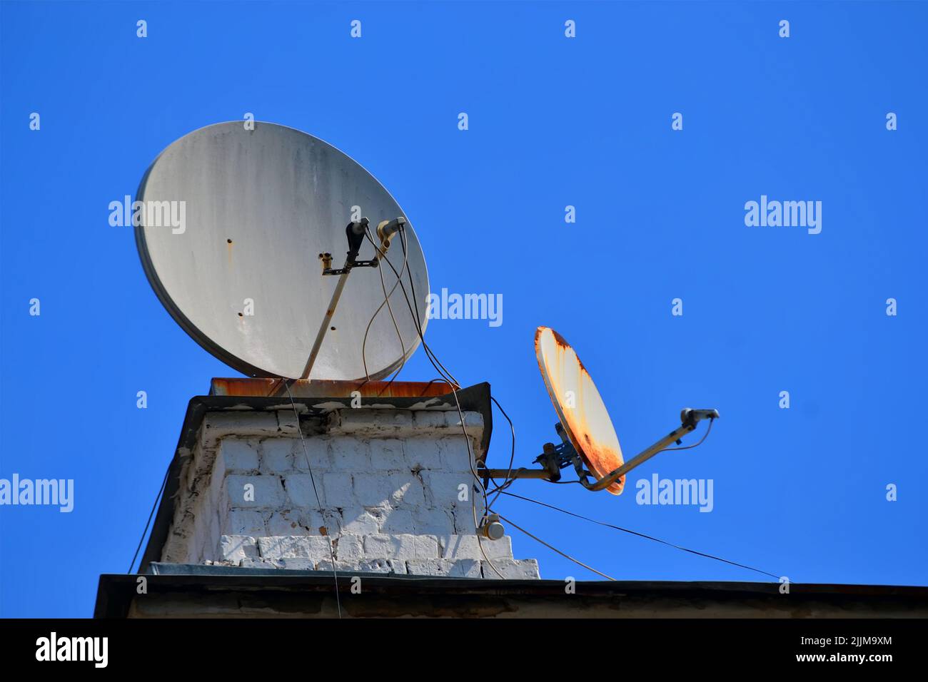 satellite dish antennas on the building roof on blue sky, modern ...