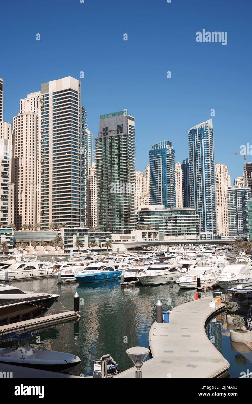 A vertical shot of the boats docked at the cityside harbor with modern ...