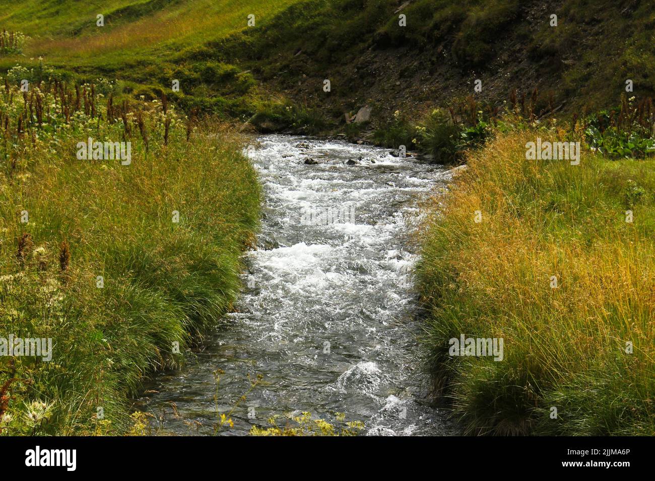 A view of a river passing through the fields and mountains Stock Photo ...