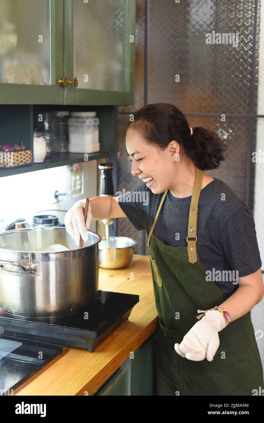 Young Vietnamese woman stirring dough in a big metal saucepan Stock ...