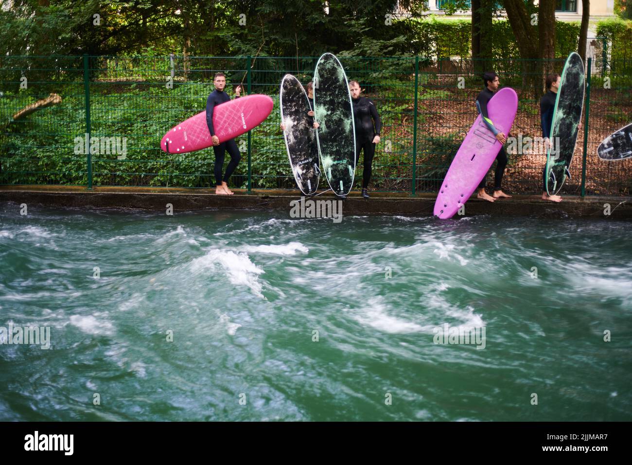 Local youth enjoying the surf in the river in the city centre of Munich ...