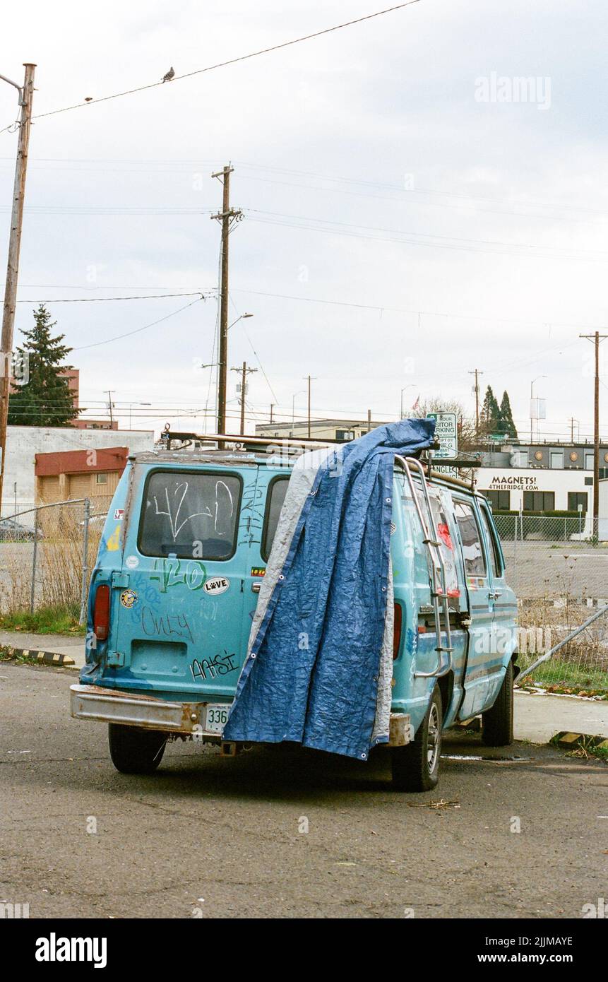 A vertical shot of an abandoned Ford van on an urban industrial street ...