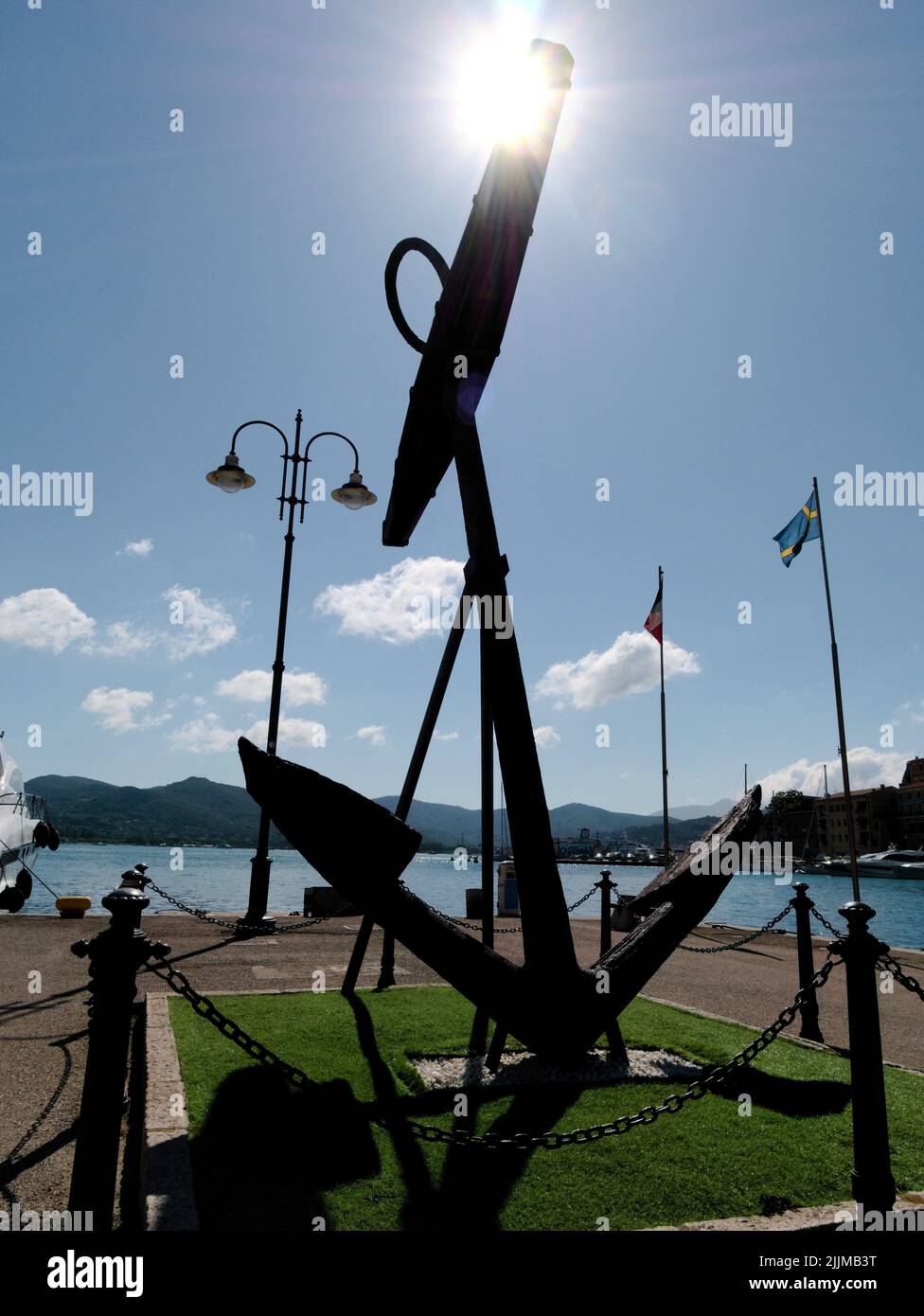 A silhouette of a monument on a sunny bay with flags and street lights ...