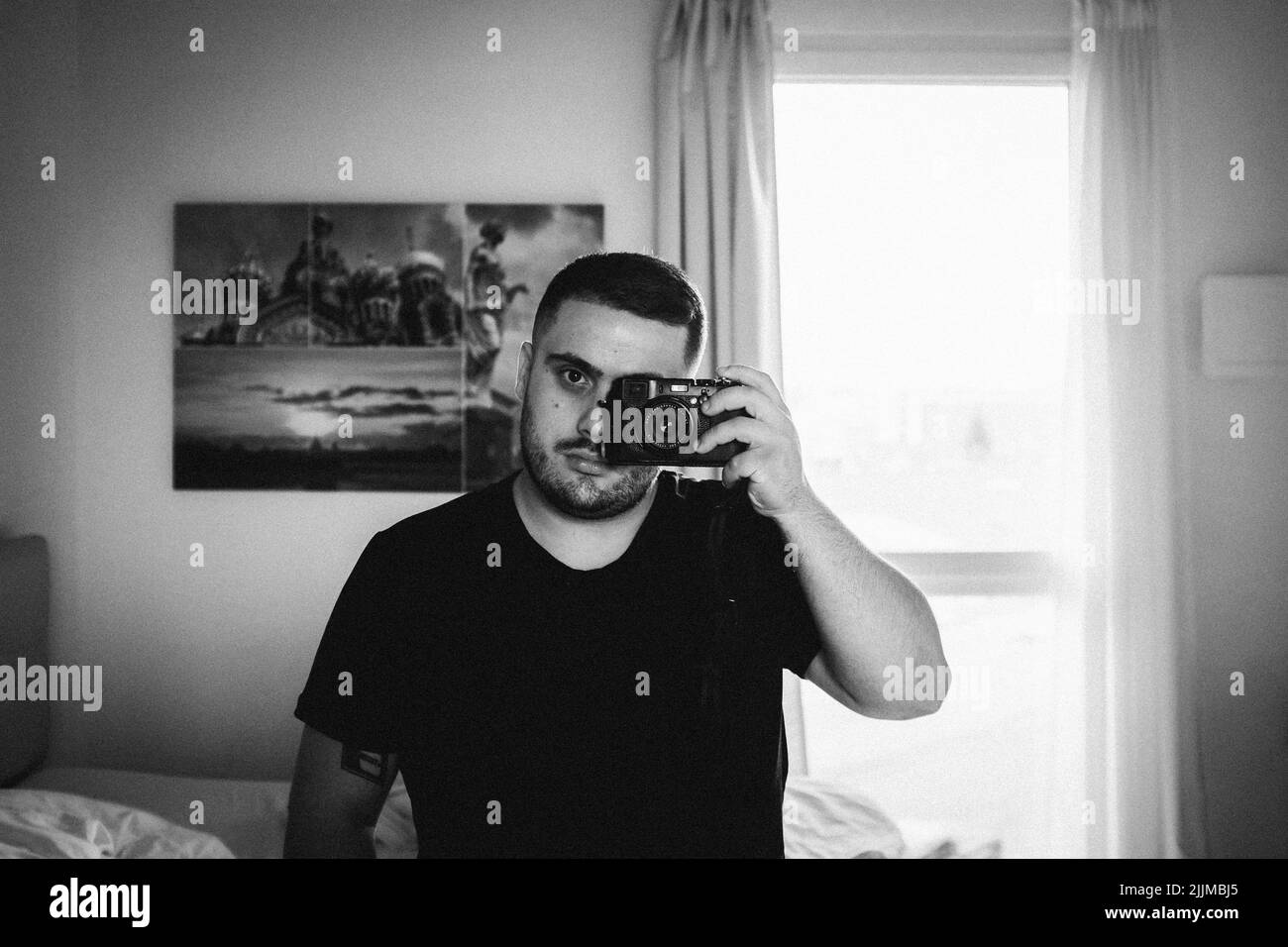 A grayscale shot of a man taking a picture with rangefinder camera in ...