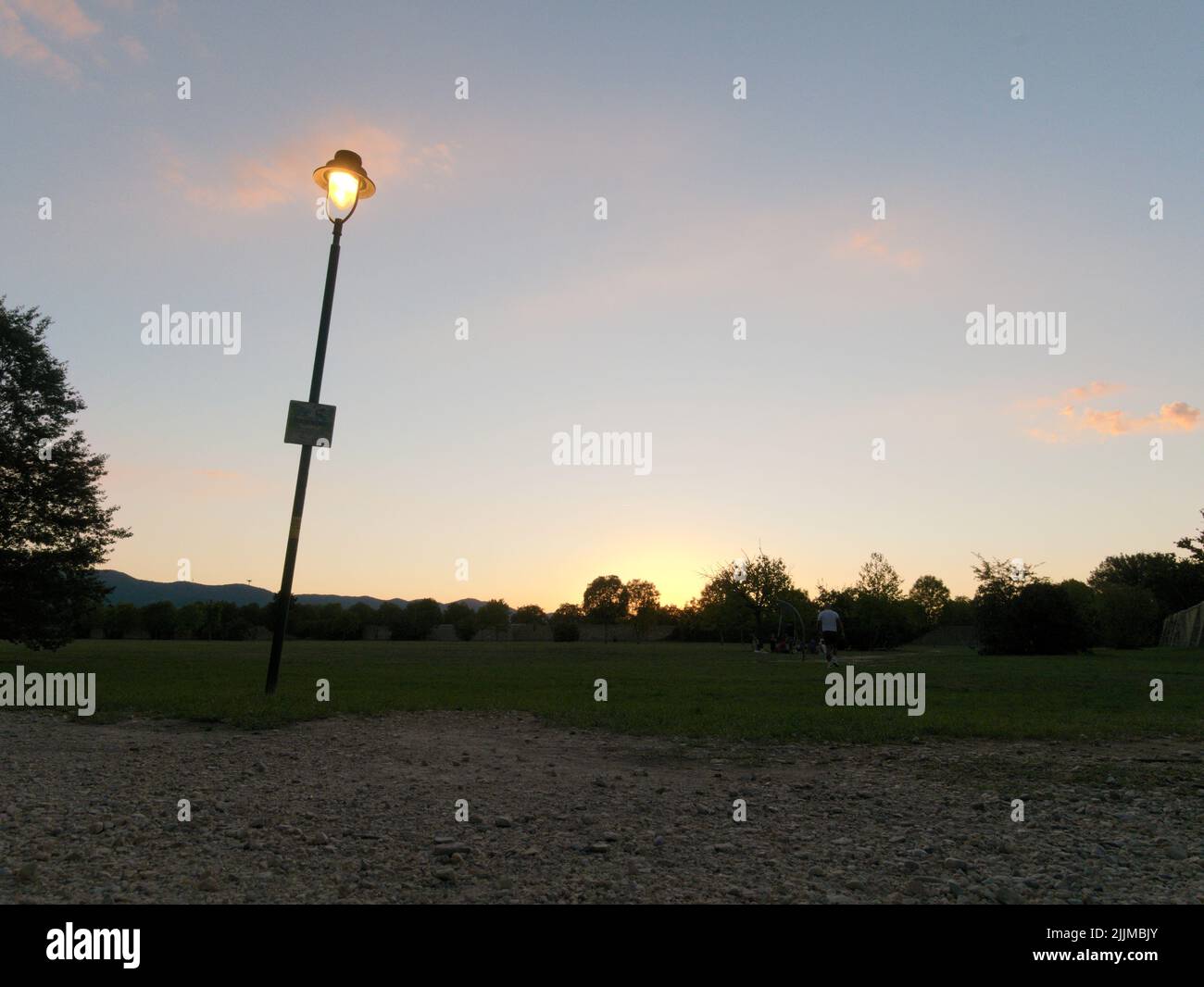 A park with an illuminated street light at sunset Stock Photo - Alamy