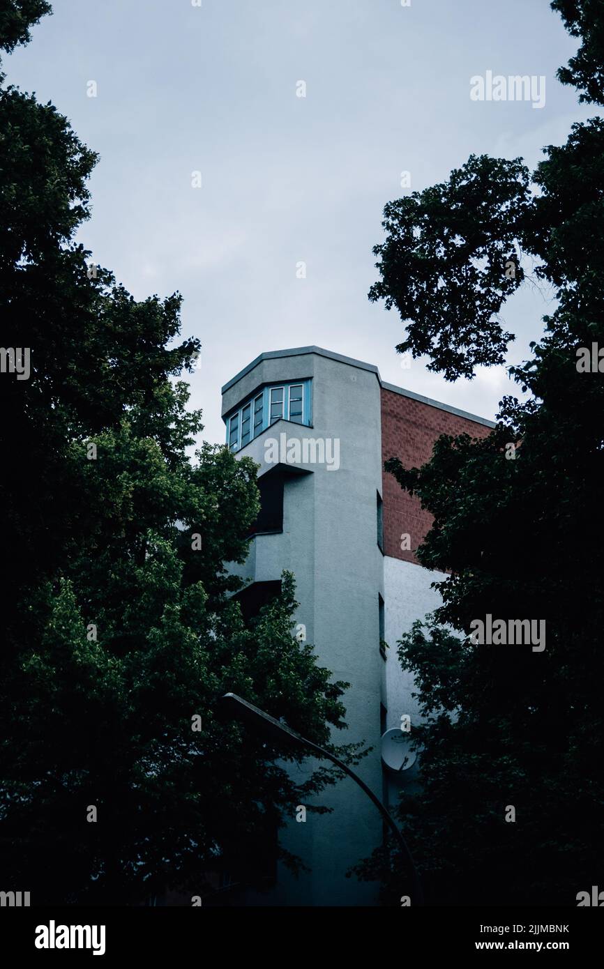 A vertical shot of a modern building hiding behind some trees Stock ...