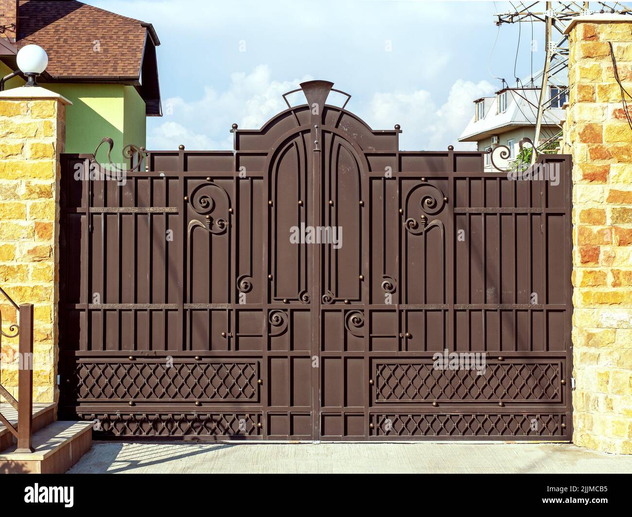 Brown iron gates with a wrought iron pattern illuminated by the sun ...