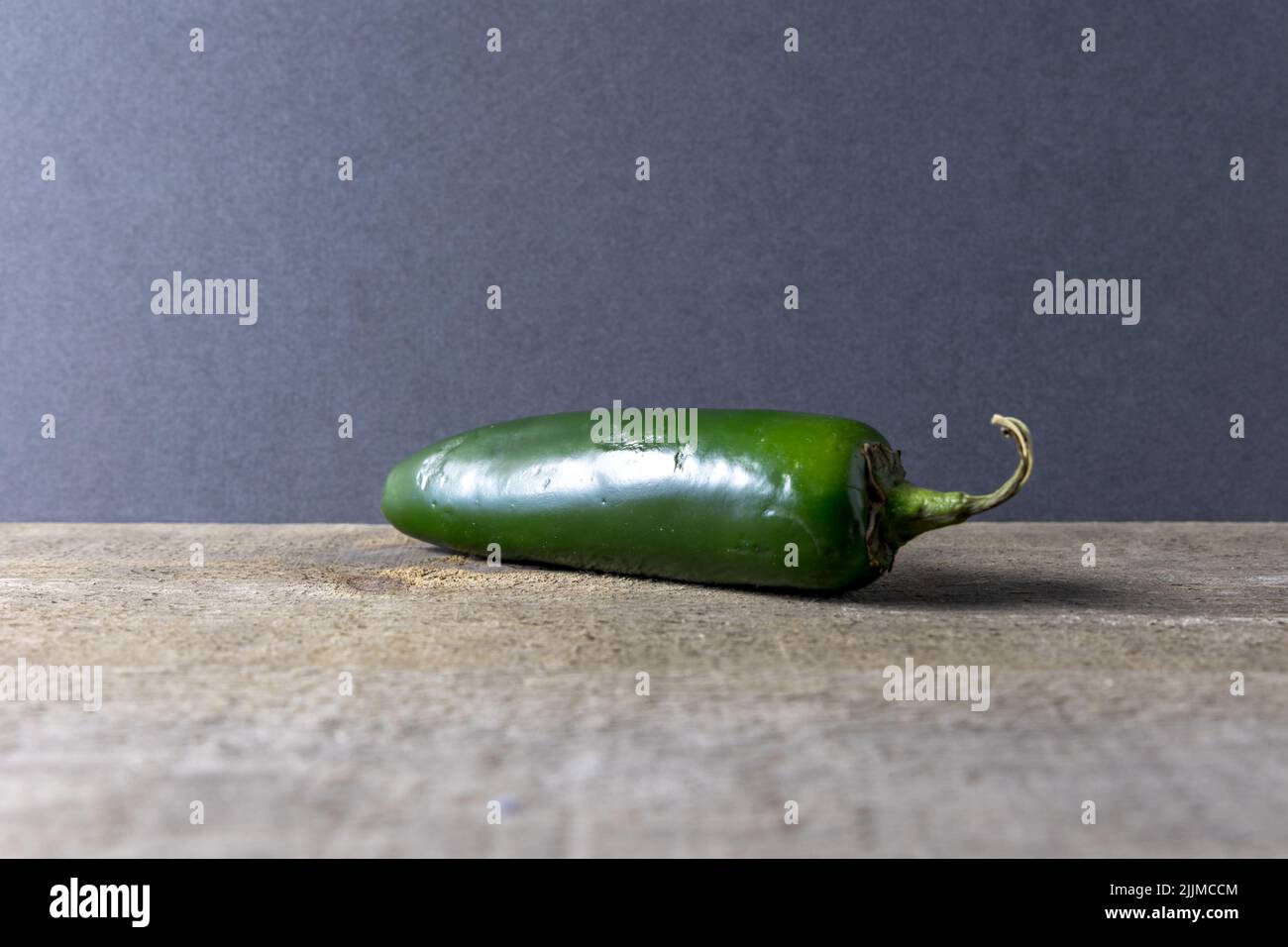 A green pepper on a surface in plain wall background Stock Photo - Alamy