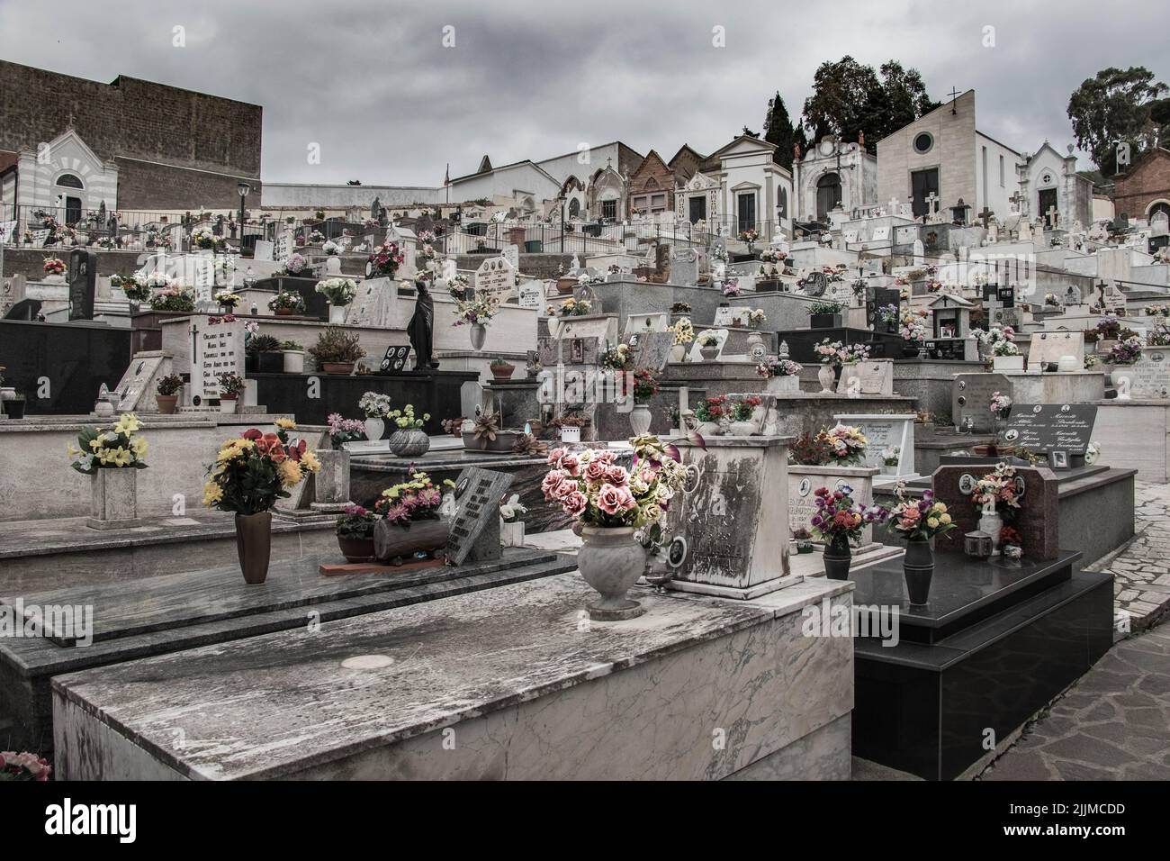 A beautiful cemetery with gravestones and flowers in cloudy sky ...