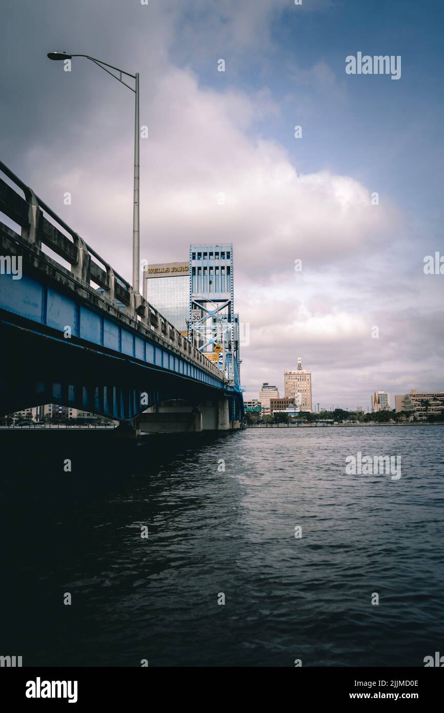 A vertical shot of a bridge over the water with coastline buildings ...