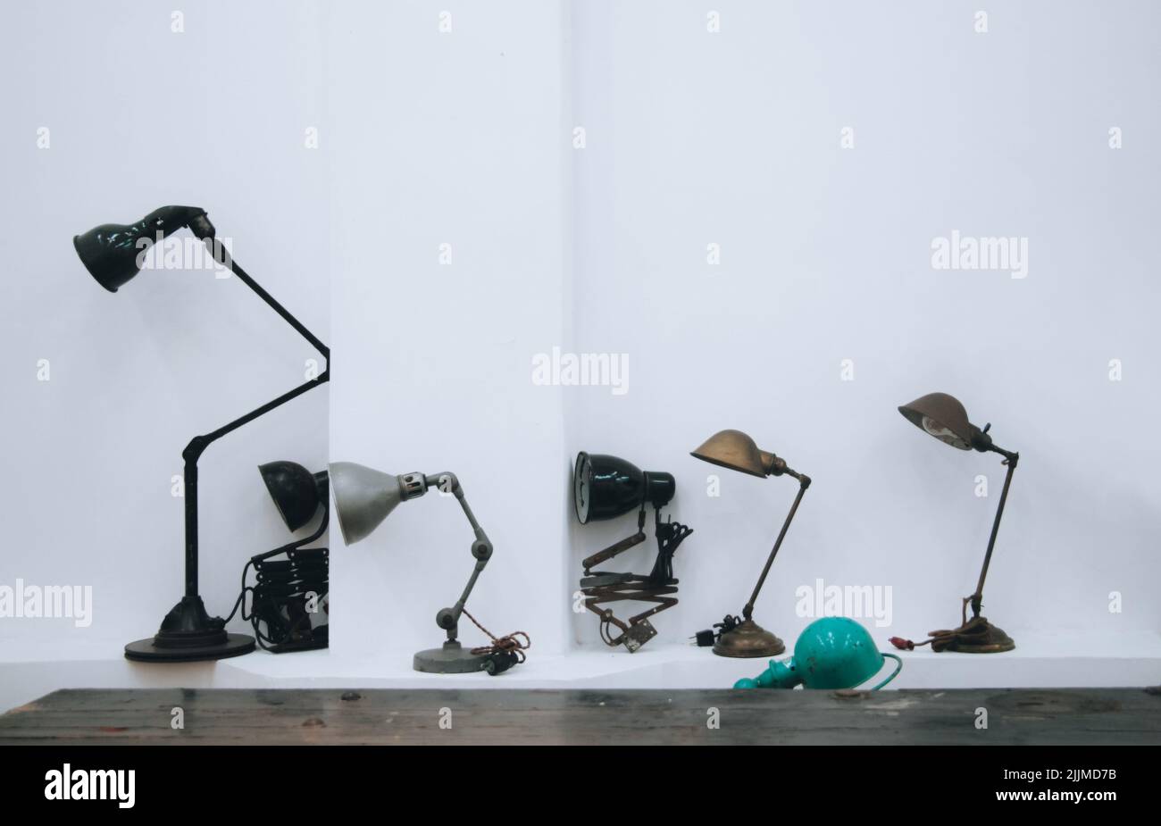 A row of different lamps on a table isolated on a white wall background ...