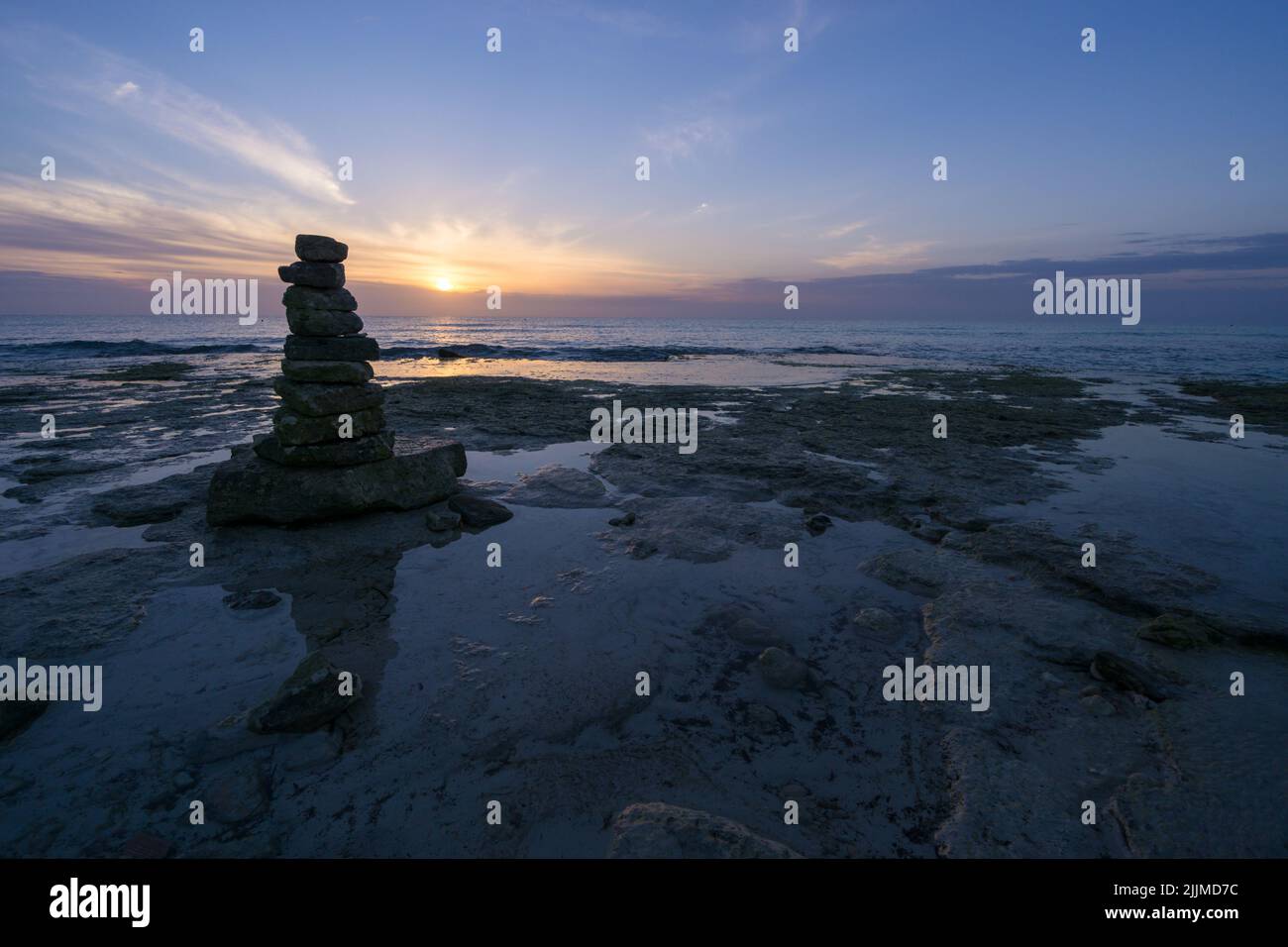 A beautiful view of a stack of balanced pebbles on the seashore at ...