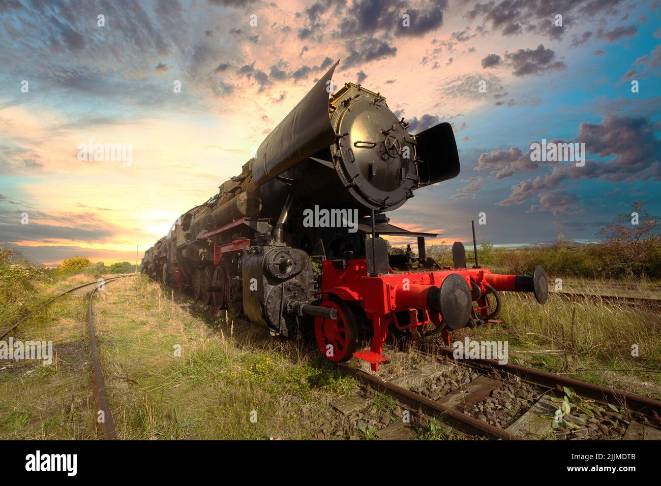A low angle shot of an industrial steel train under a bright sunset sky ...