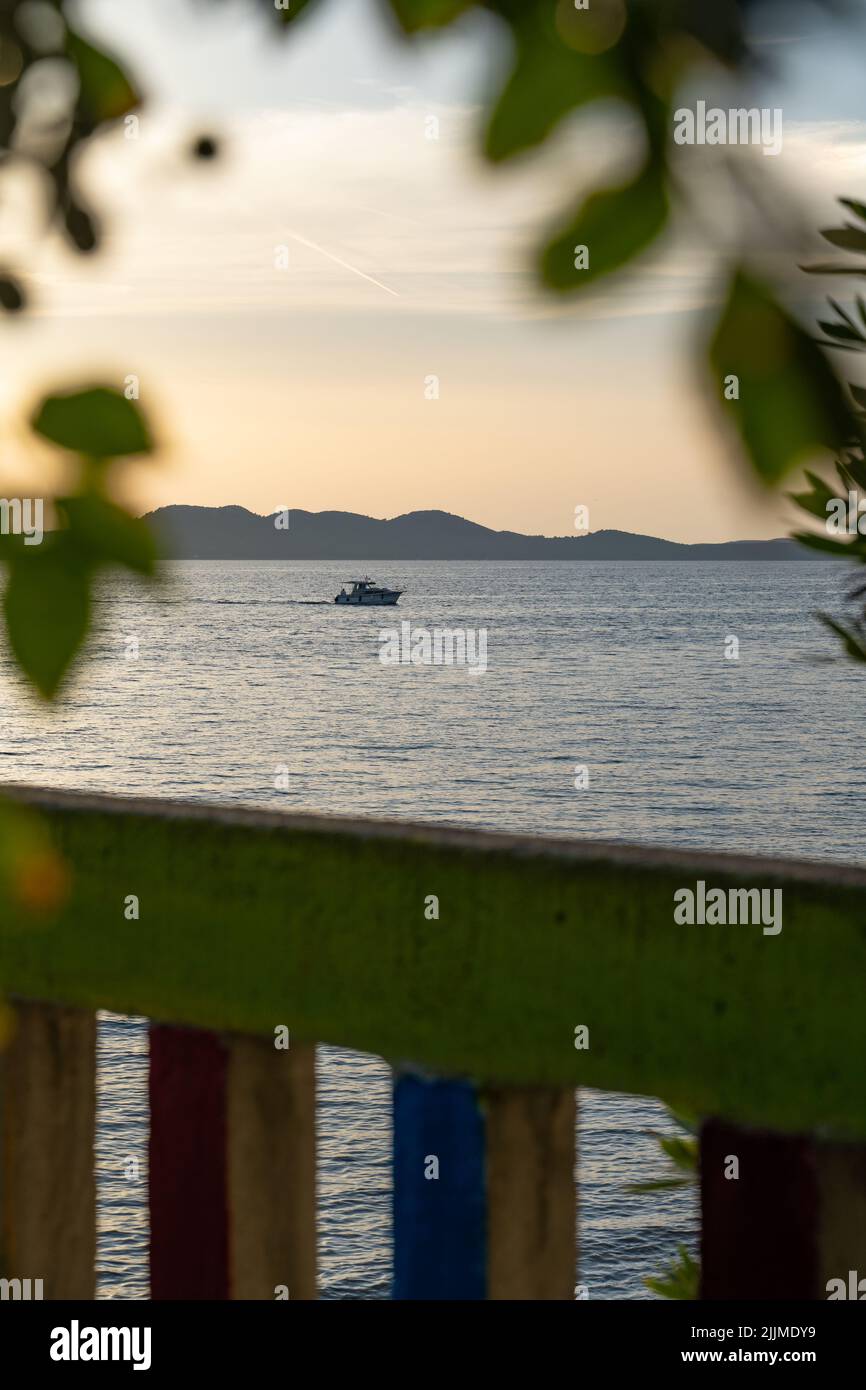 A distant view of a boat sailing in the sea during the sunset Stock ...
