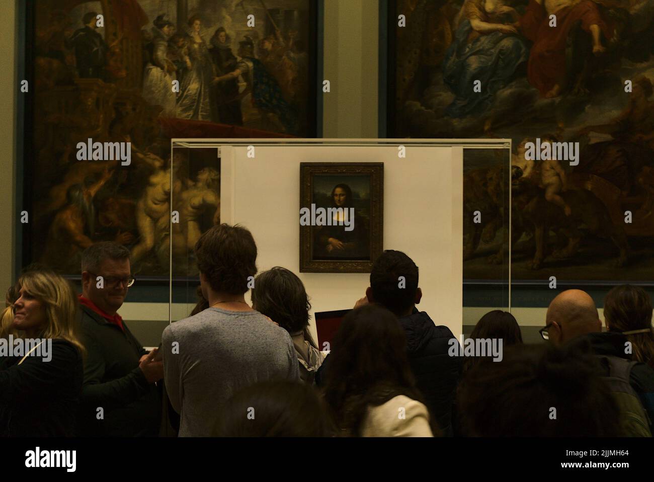 A group of tourists observing the painting of Mona Lisa in the Louvre Museum, Paris, France ...