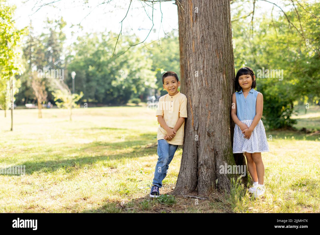 Cute Asian kids posing by the tree in the park Stock Photo - Alamy
