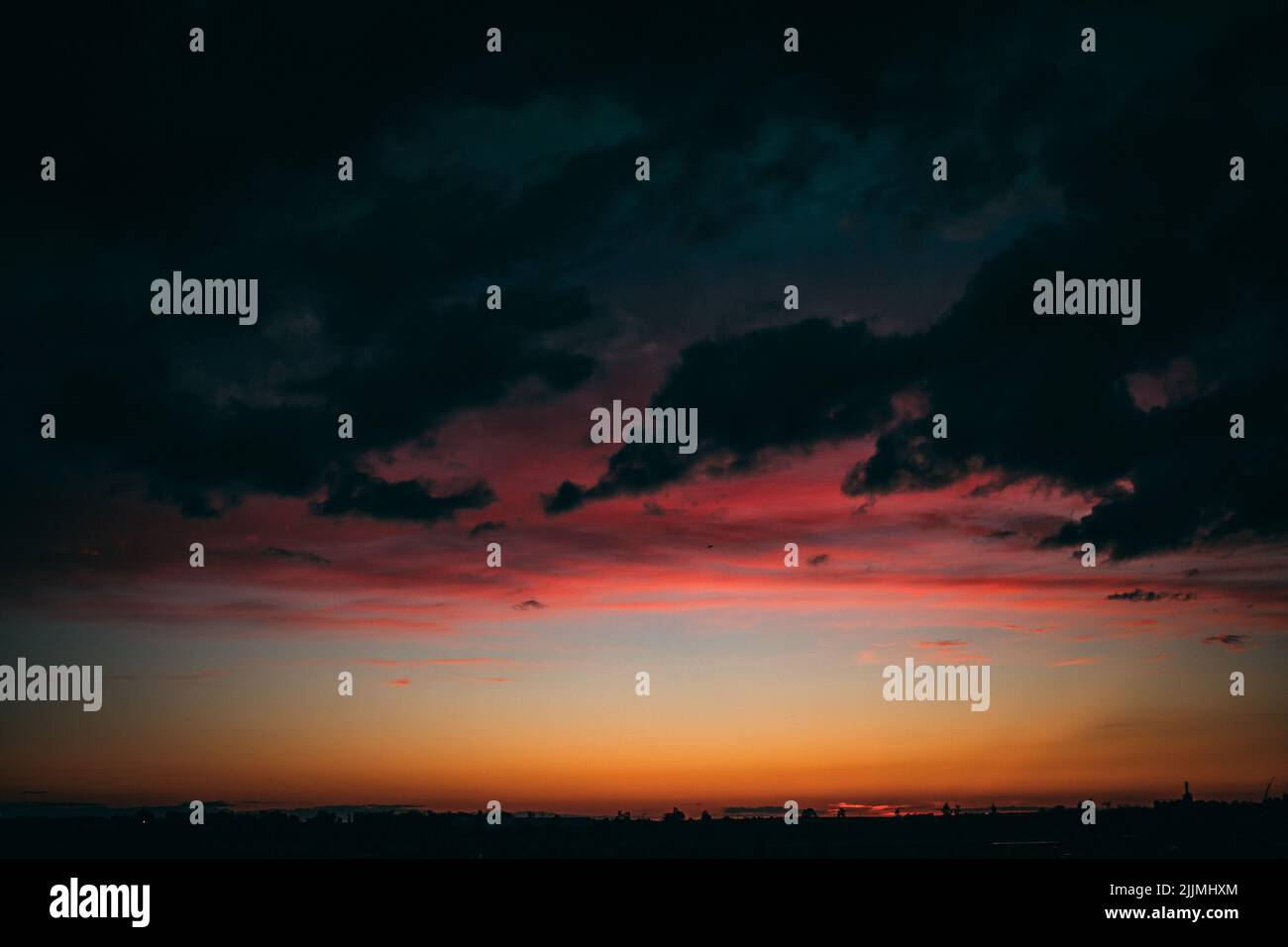 A mesmerizing scene of colorful sunset sky with dark clouds with red ...