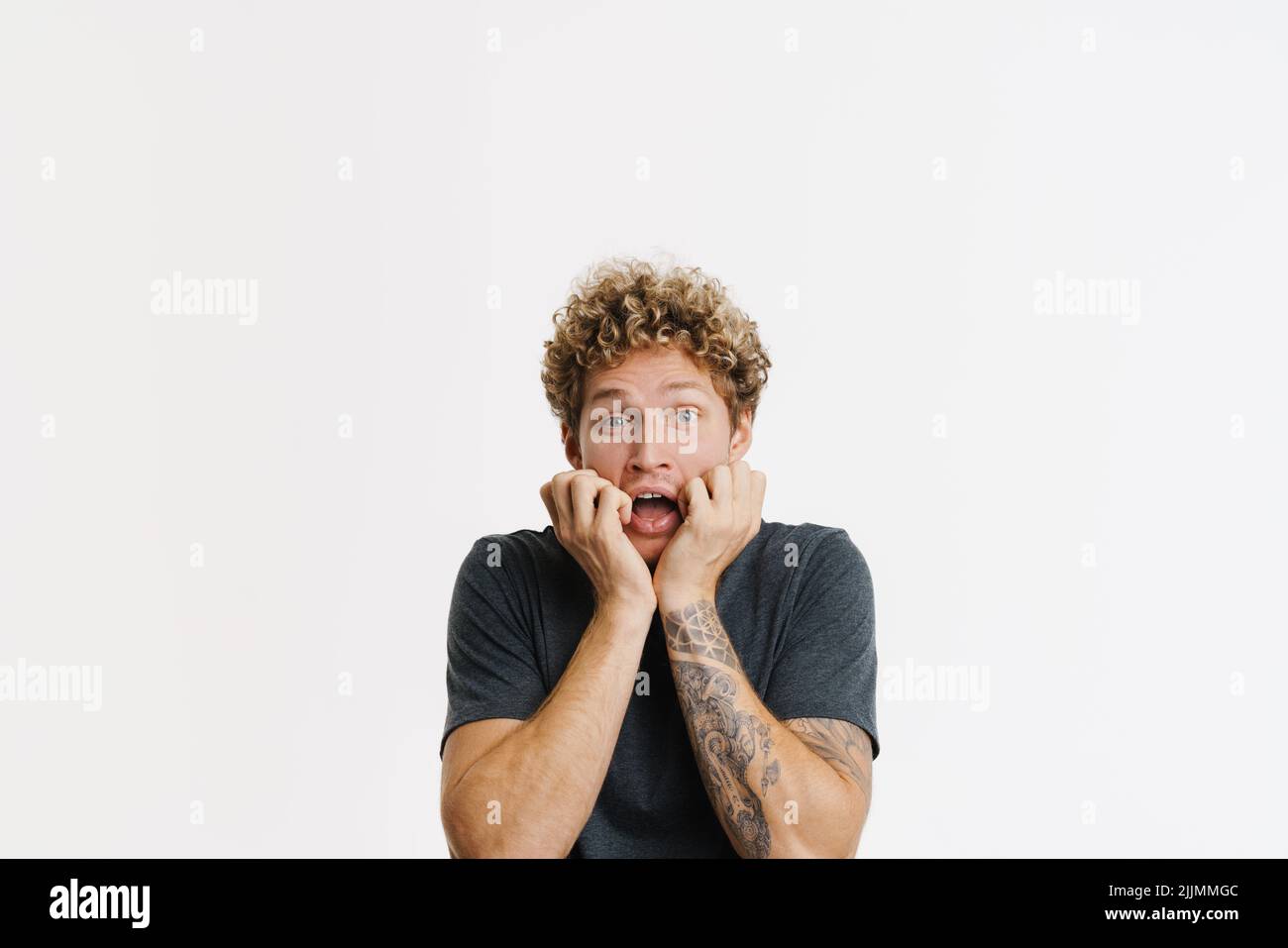 Young curly man expressing surprise and screaming at camera isolated ...