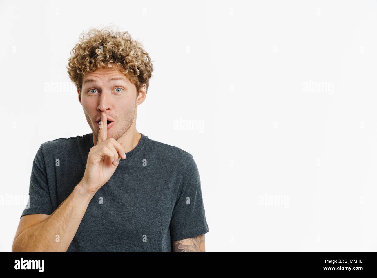 Young man expressing surprise while making winner gesture isolated over ...