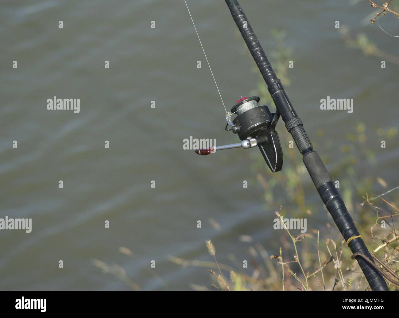 a fishing stick on a river shore with a water flowing in behind Stock ...