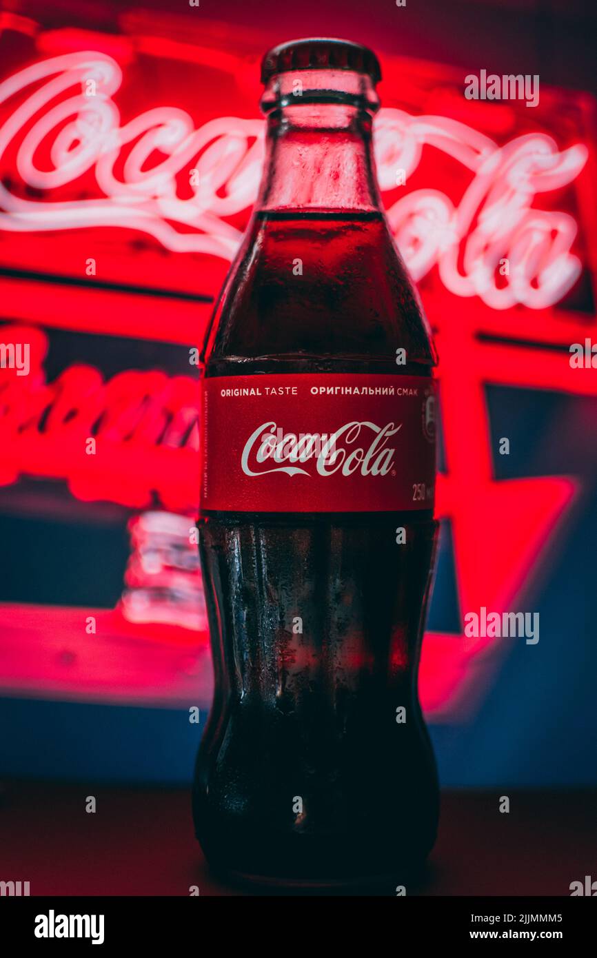 A vertical shot of a red coca-cola bottle against a blurred background ...