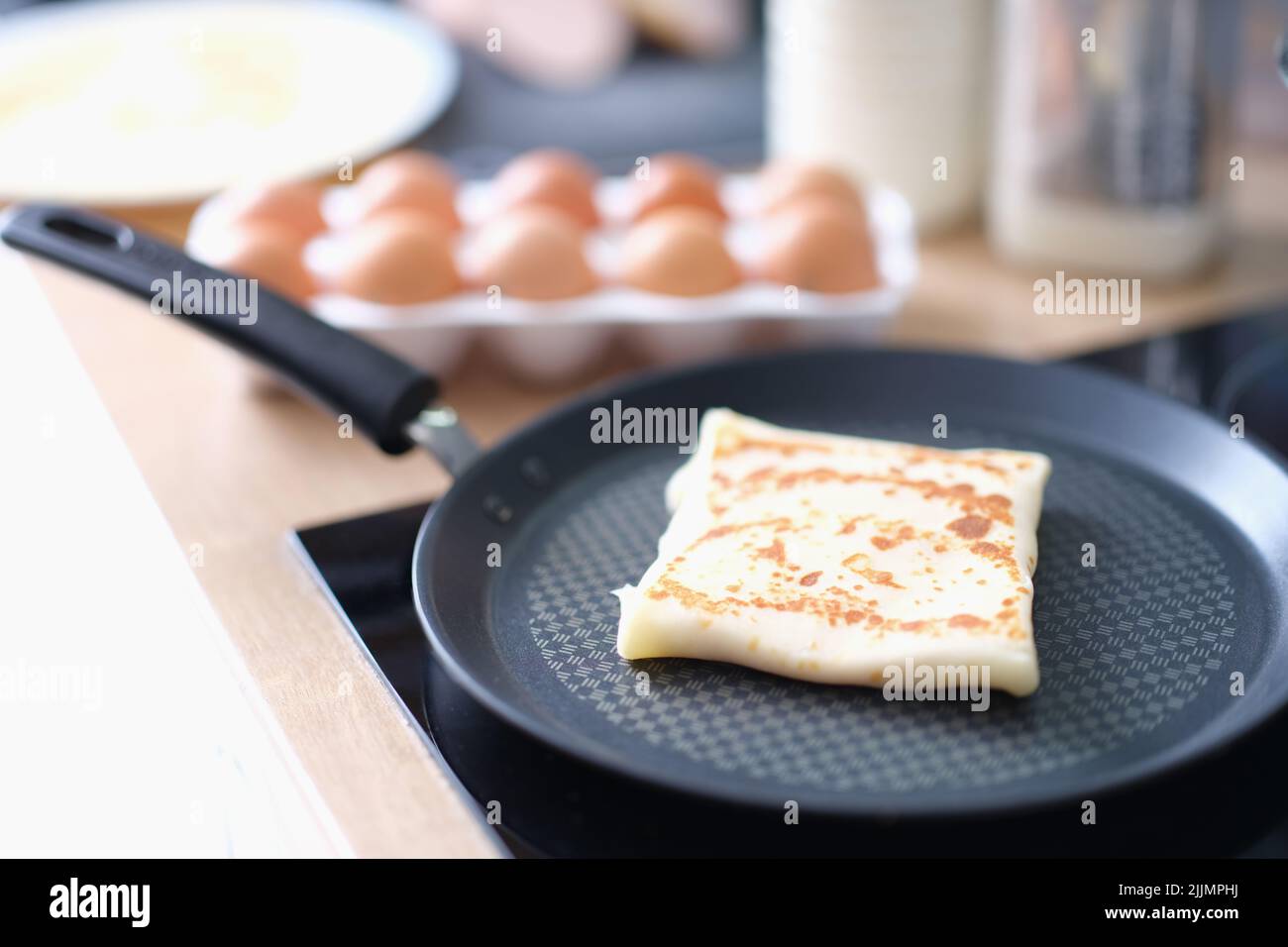 Folded pancake in frying pan against background of chicken eggs in ...
