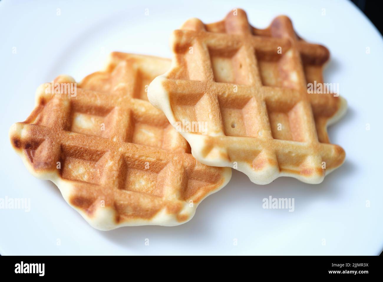 Two freshly baked Belgian waffles on white plate Stock Photo - Alamy