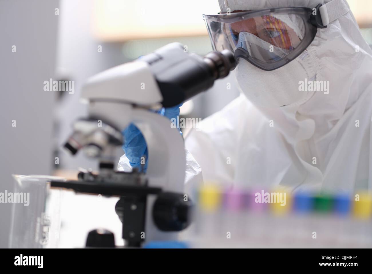 Biologist in protective suit with goggles and medical mask working with ...
