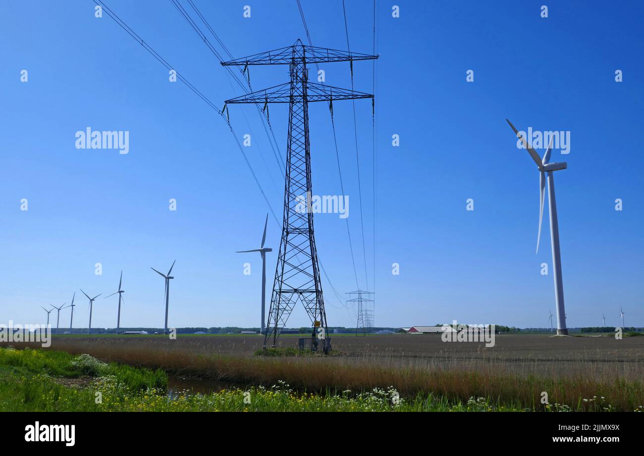 A row of wind turbines combined with high voltage power pylons Stock ...