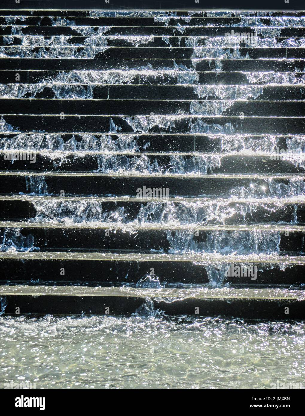 Close-up of sparkling water spashing down concrete stairs in a fountain ...