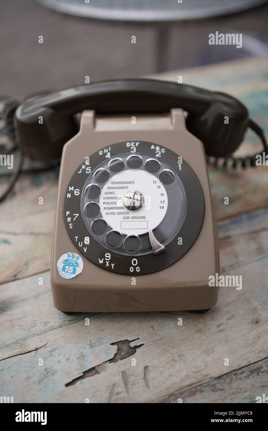 A vertical shot of an old fashioned phone set on a wooden table. La ...