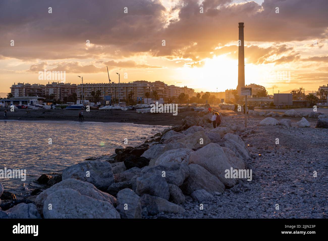 A scenic view of the sun hiding behind the city buildings during sunset ...