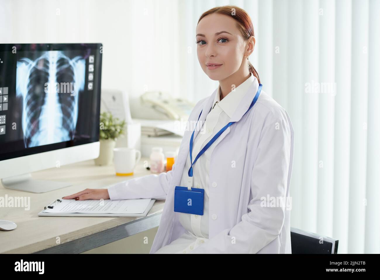Portrait of young female pulmonologist checking x-ray of recovering ...