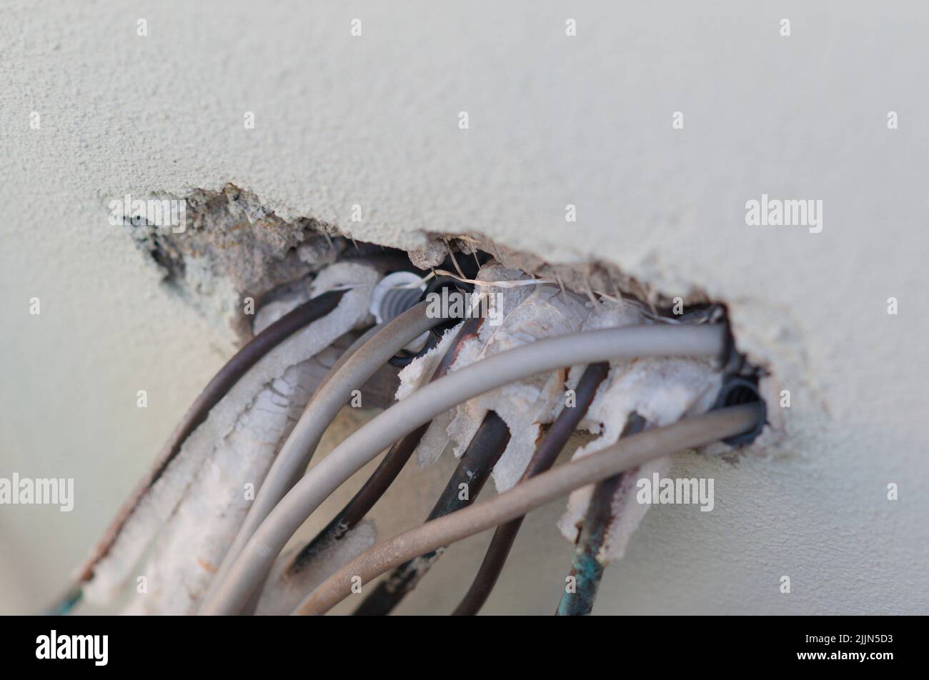 A closeup of a bundle of cables sticking out of a wall Stock Photo - Alamy