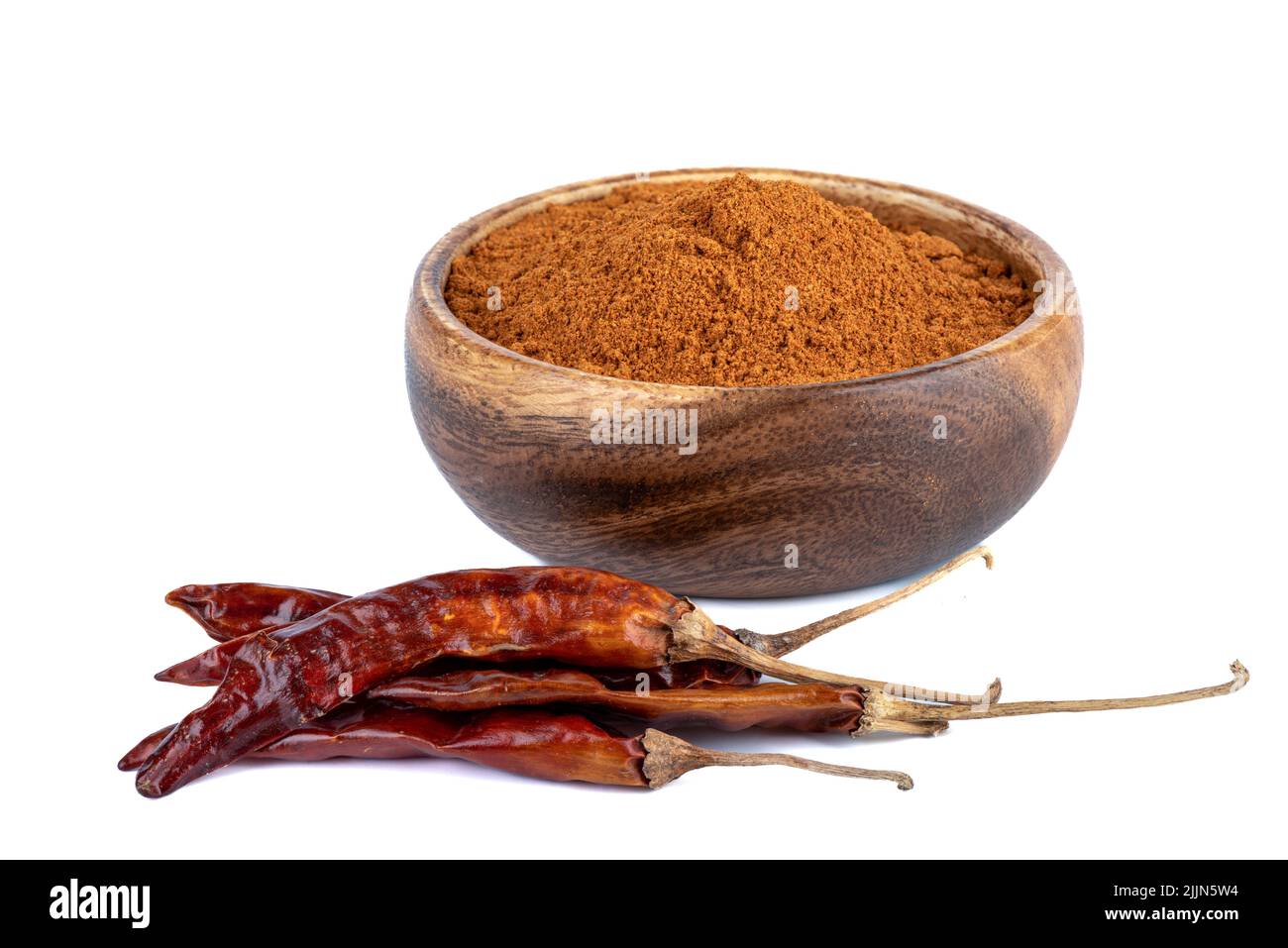 Dried hot pepper pods and ground pepper in a bowl over a white ...