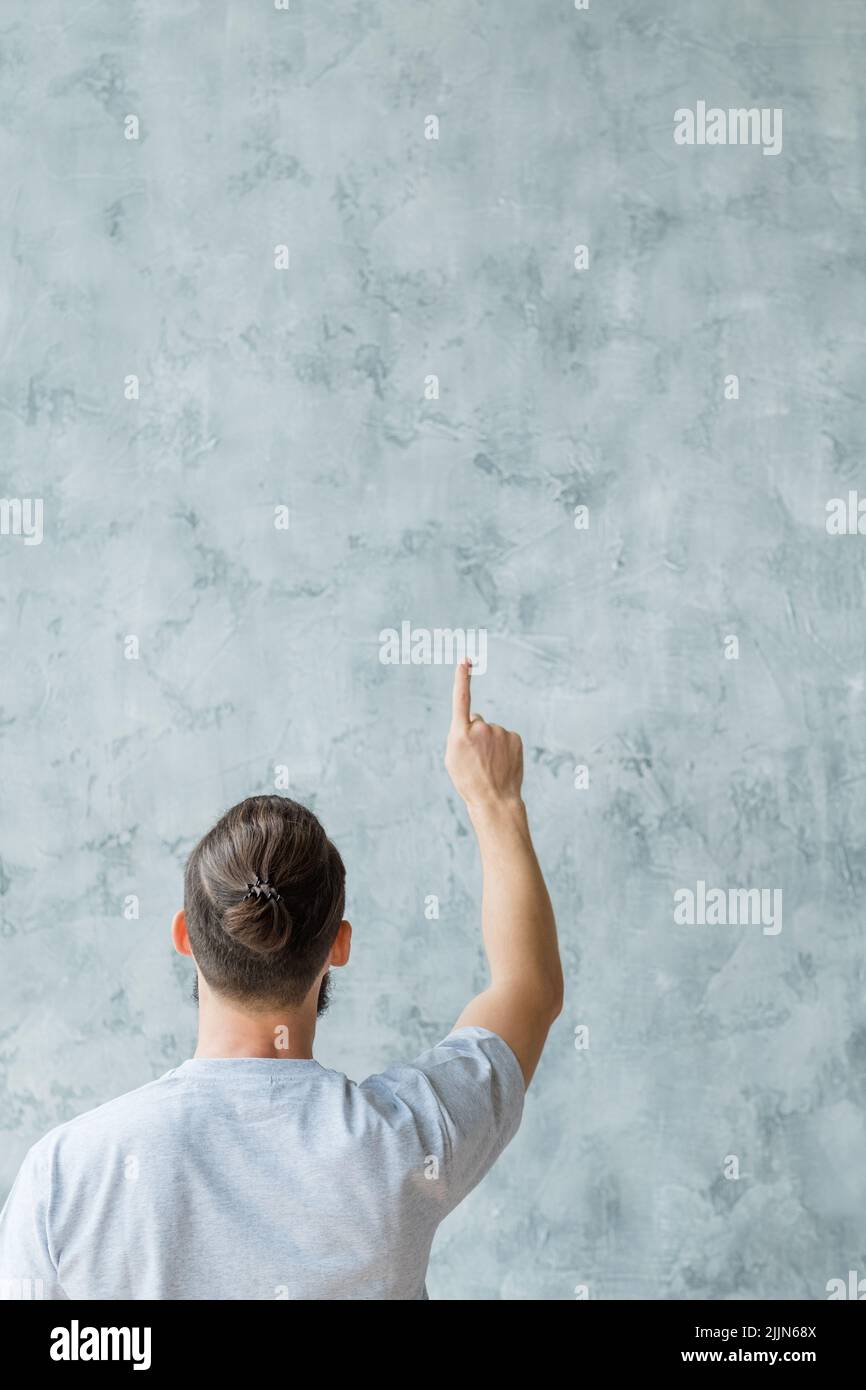 back view man stucco background point index finger Stock Photo - Alamy