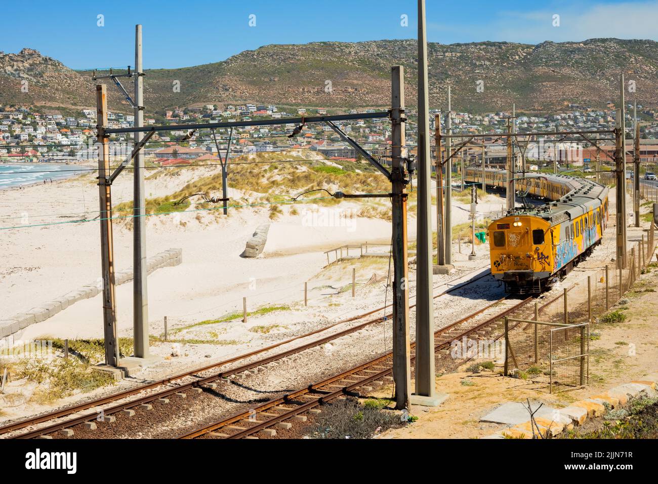 A closeup of a Passenger Railway running along the beach in the small ...