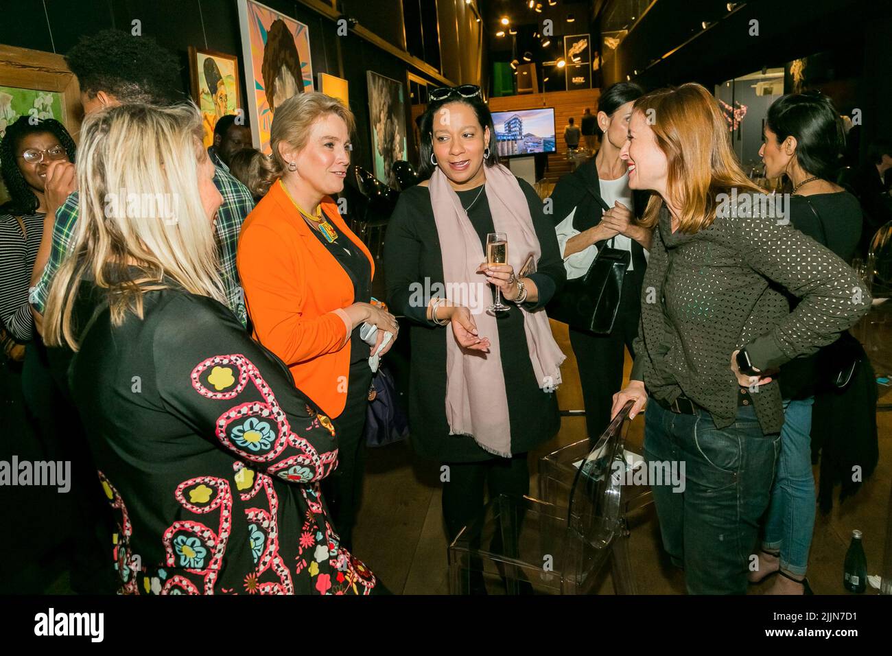 The VIP Caucasian female guests chatting at a social event in an art ...