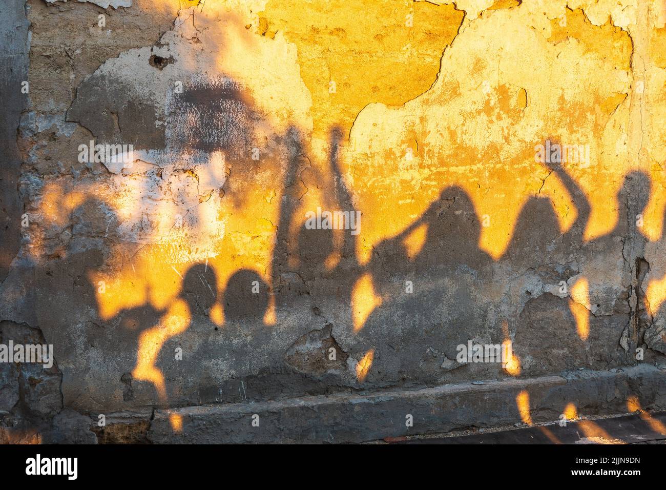 Shadows of dancing people on an old wall at sunset time. Group of human ...