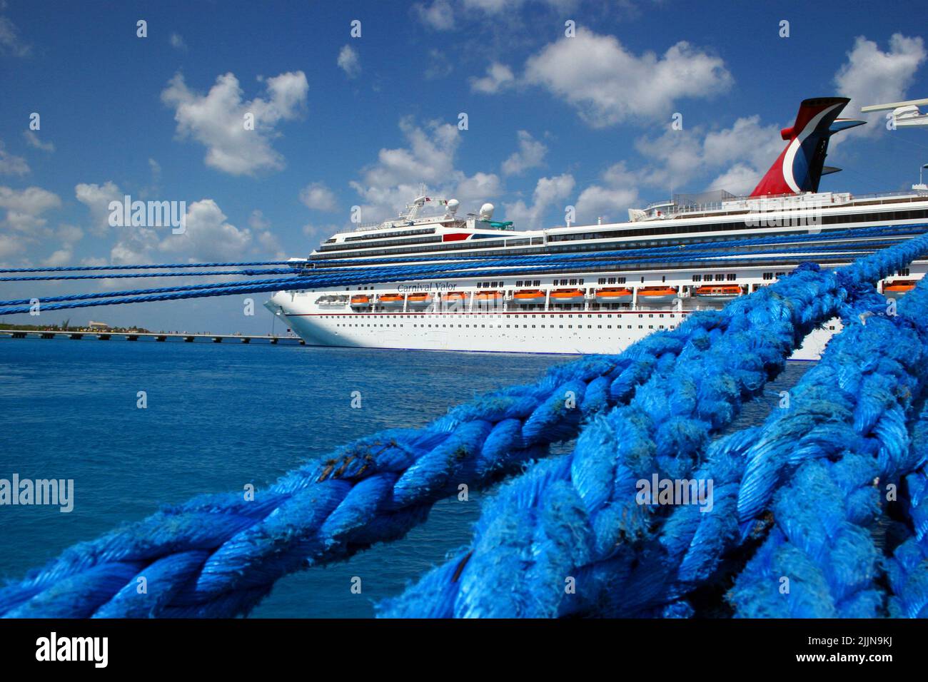 A profile view of a luxury cruise ship connected with thick ropes Stock ...
