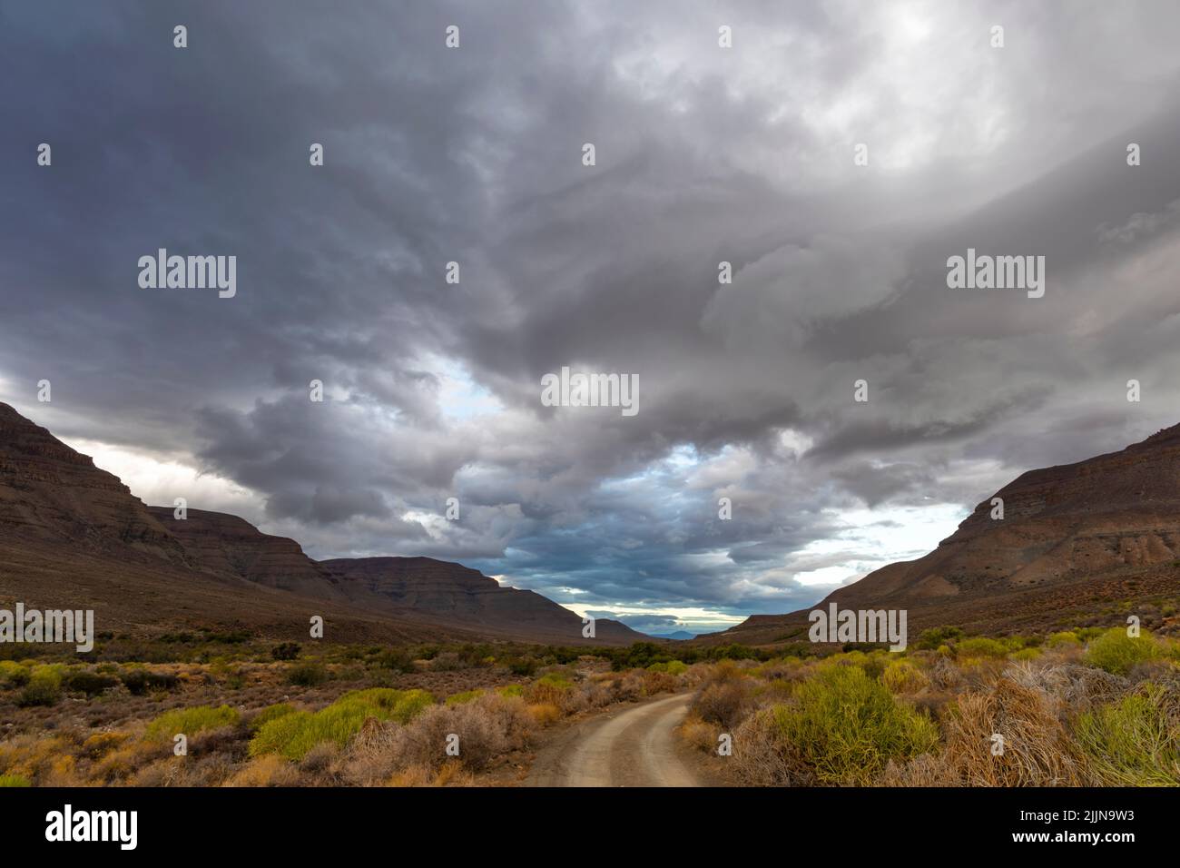 Dirt track between mountains with low clouds above Tankwa Karoo NP ...