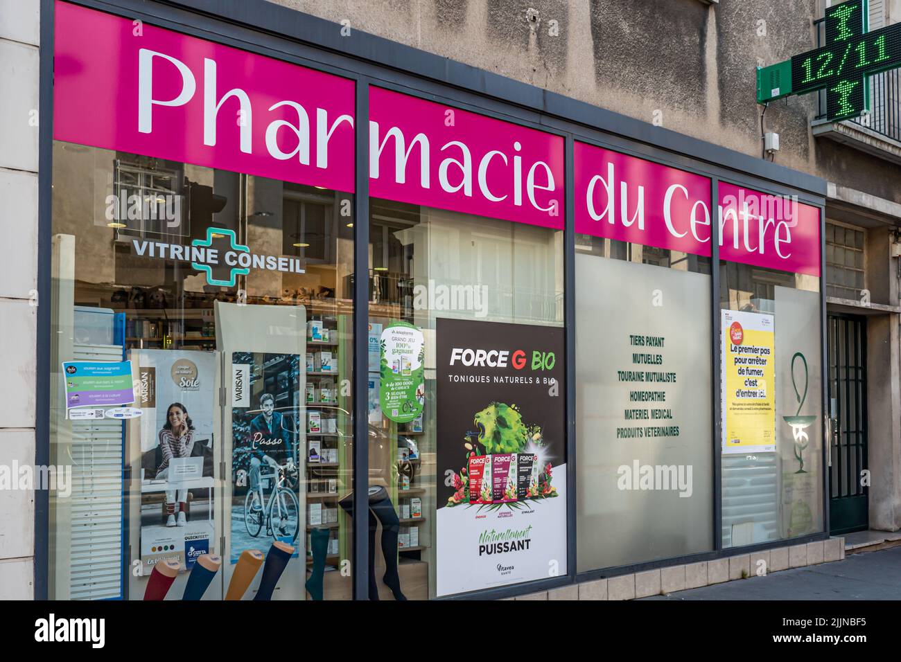 A French pharmacy (Pharmacie du Centre) side store facade view with ...