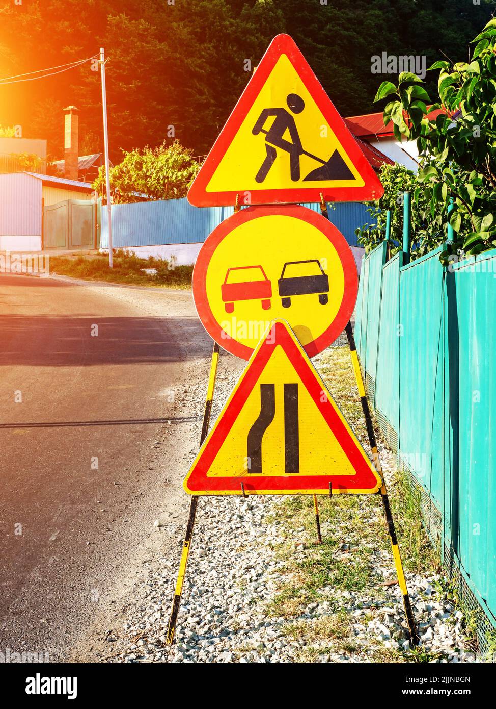Yellow-red warning signs on the gravel side of a rural road. Road works ...