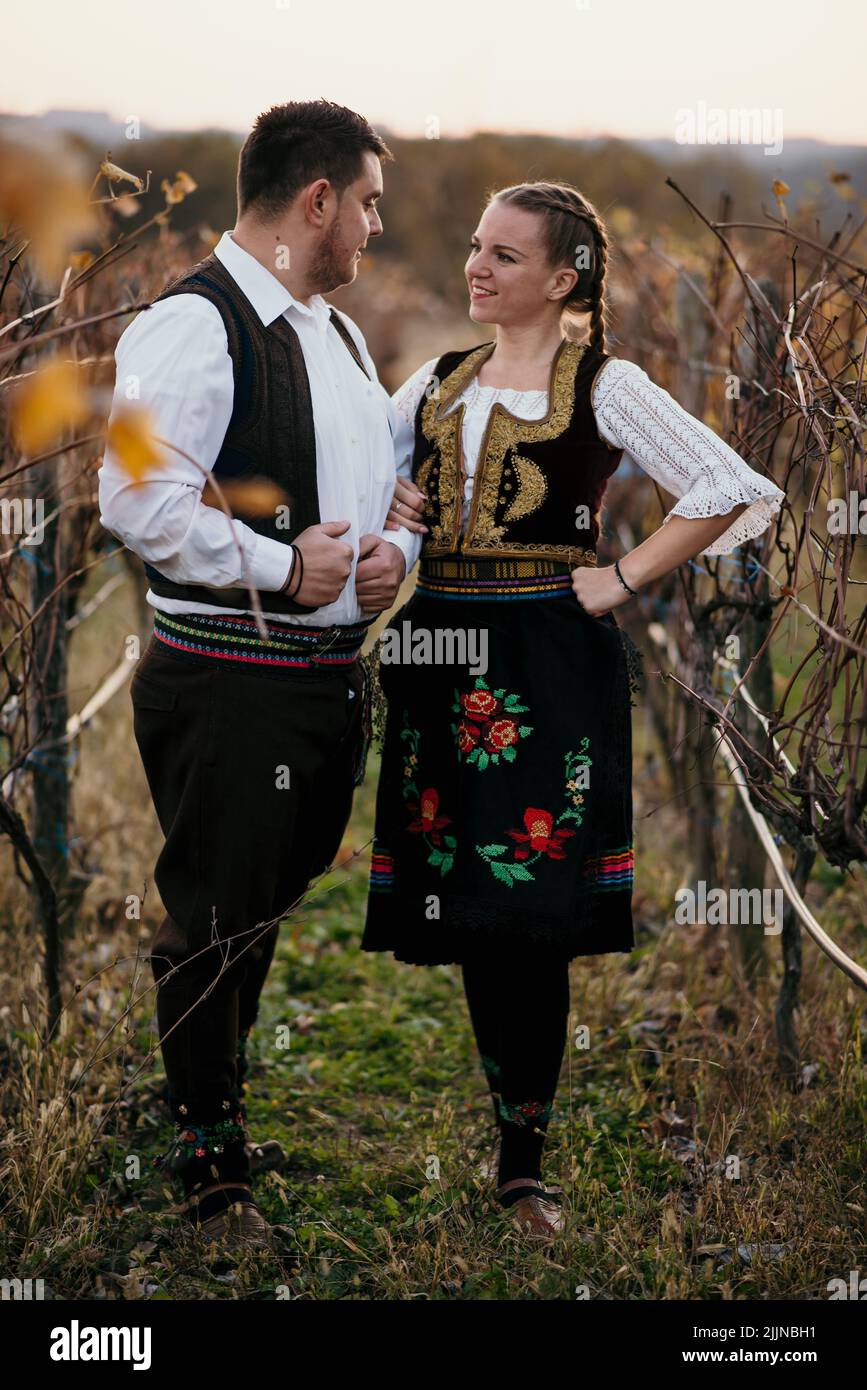 A vertical shot of a Serbian couple in traditional costumes posing for ...