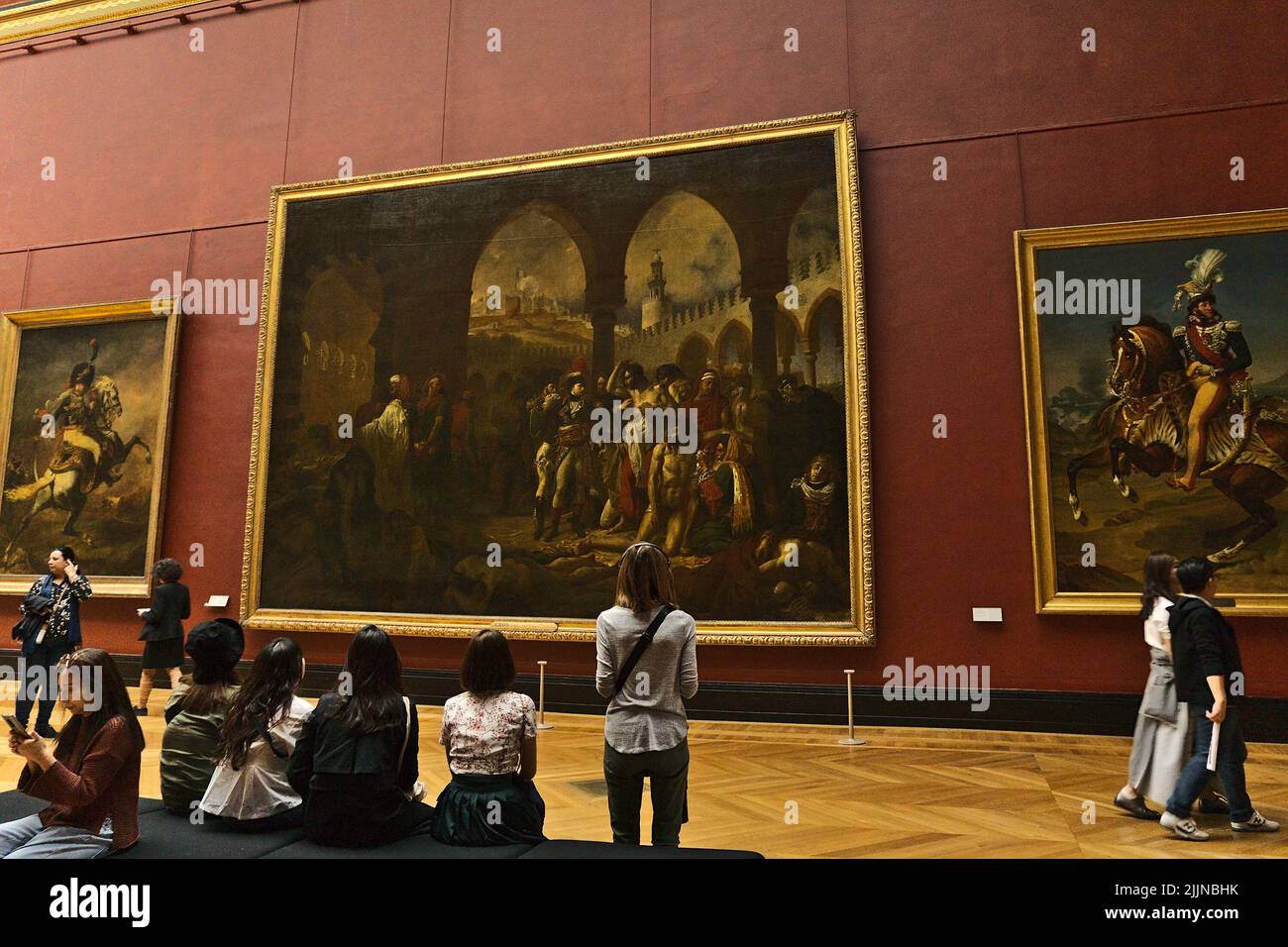 A group of visitors looking at a painting at the Louvre museum, Paris ...
